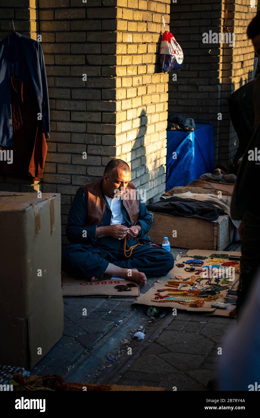 Iraq, Iraqi Kurdistan, Arbil, Erbil. A man is sitting on the ground at ...