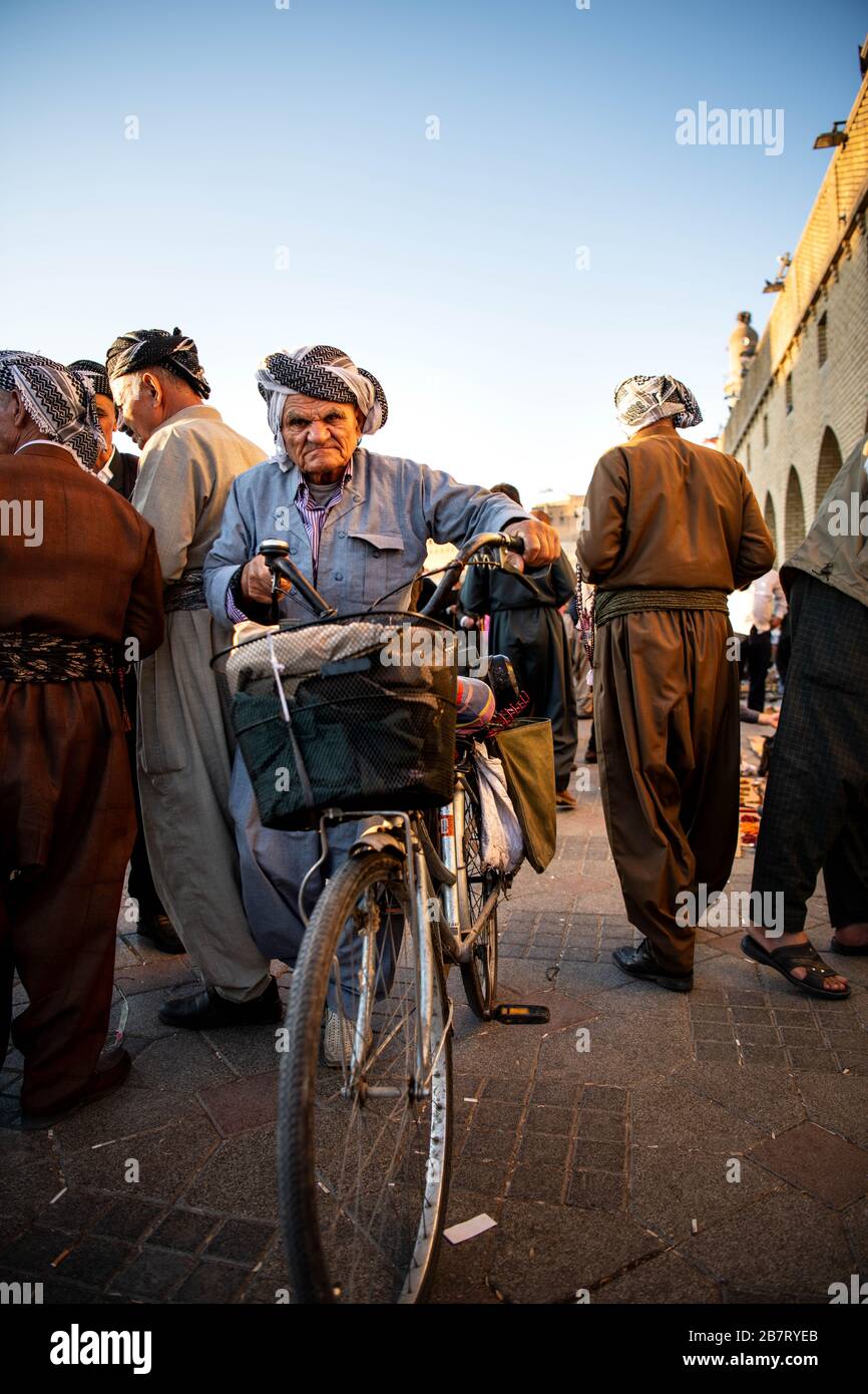 Iraq, Iraqi Kurdistan, Arbil, Erbil. A man is pushing a bicycle on a ...