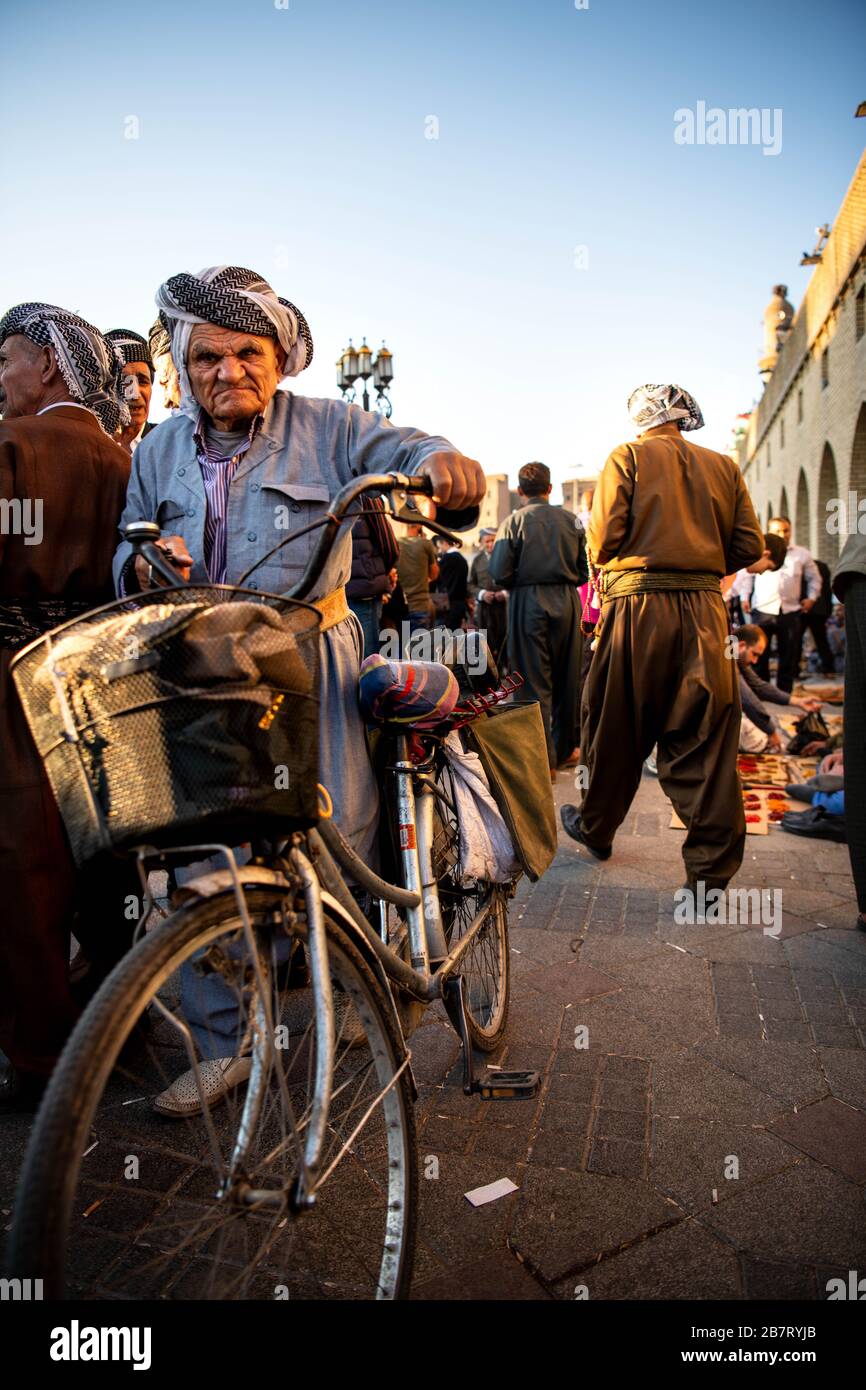 Iraq, Iraqi Kurdistan, Arbil, Erbil. A man is pushing a bicycle on a ...