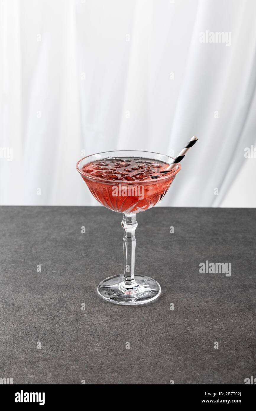 glass with red cosmopolitan cocktail with ice and straw on white Stock ...