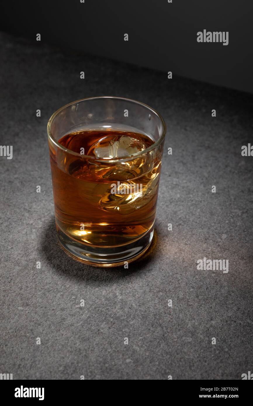 ice cubes in glass of brandy on grey surface Stock Photo - Alamy