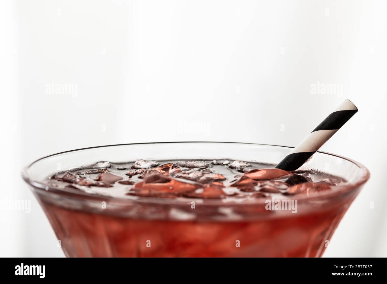 selective focus of cosmopolitan cocktail with striped straw and ice ...