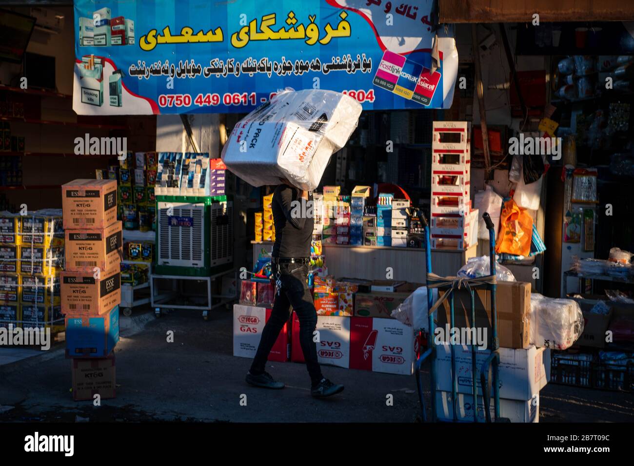 Iraq, Iraqi Kurdistan, Arbil, Erbil. A man is carrying a big package on ...