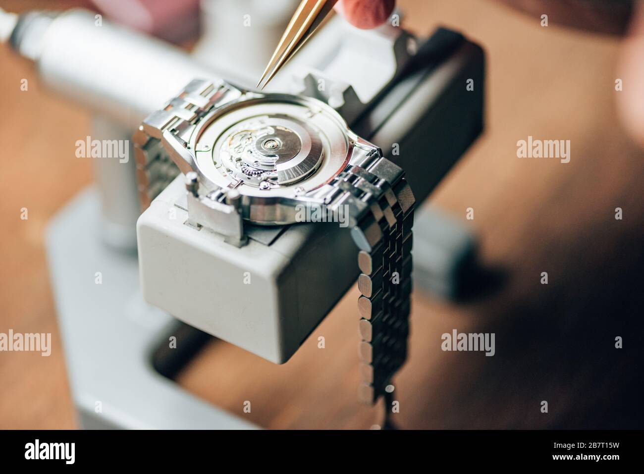 Cropped view of watchmaker working with tweezers and wristwatches on ...