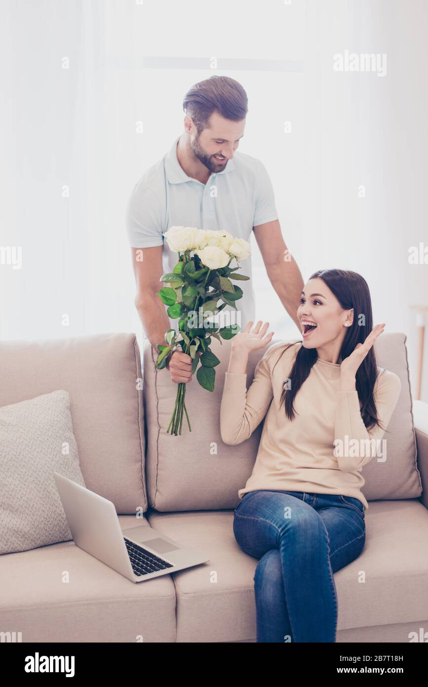 Surprised young woman receiving flowers from her husband. It`s ...