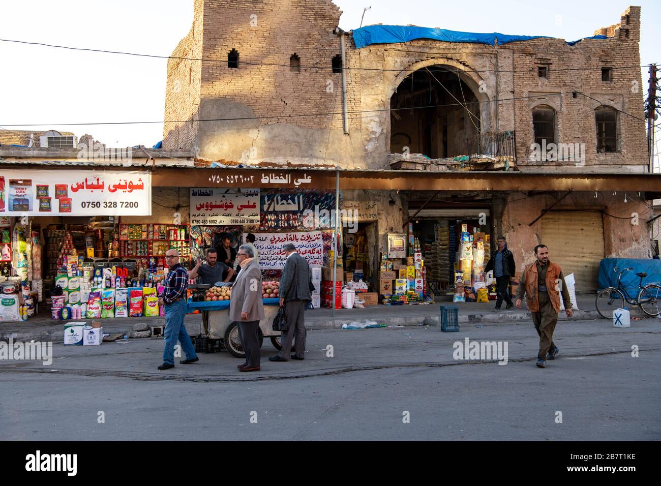 Iraq, Iraqi Kurdistan, Arbil, Erbil. Three men gather around a fruit ...