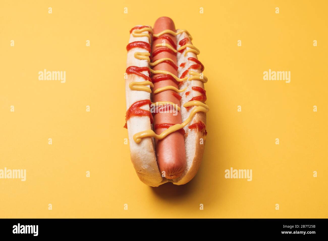 delicious unhealthy hot dog with sausage, mustard and ketchup on yellow ...