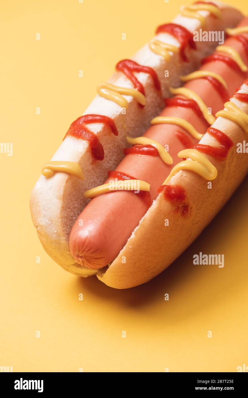 close up of unhealthy hot dog with sausage, mustard and ketchup on ...