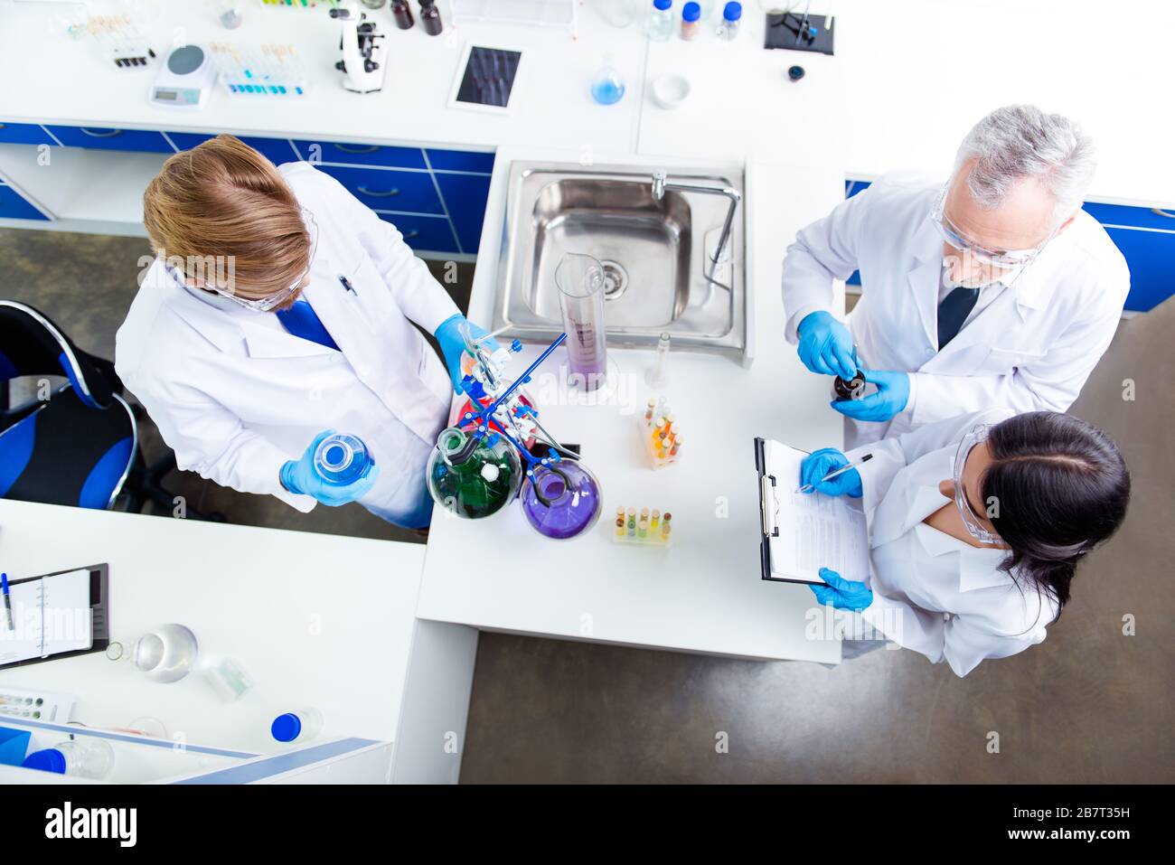 Top view of team work of three scientists, making tests with chemicals ...