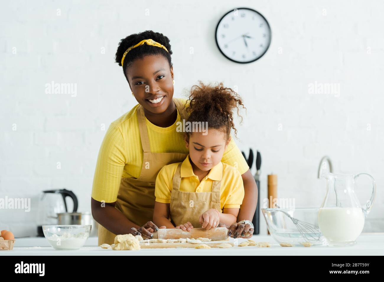cute african american kid holding rolling pin near cheerful mother and ...