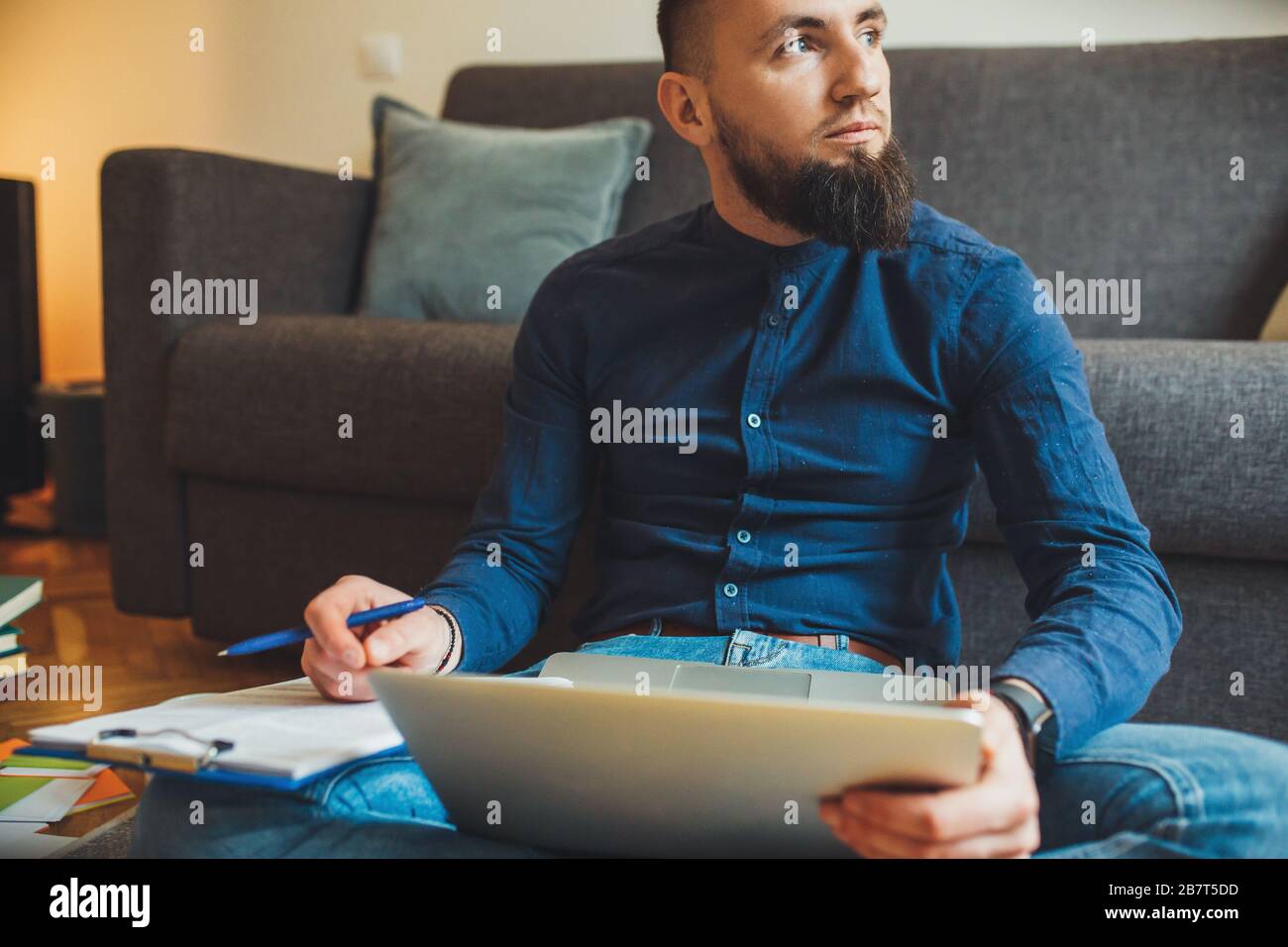 Bearded businessman working on the floor at the computer with some ...