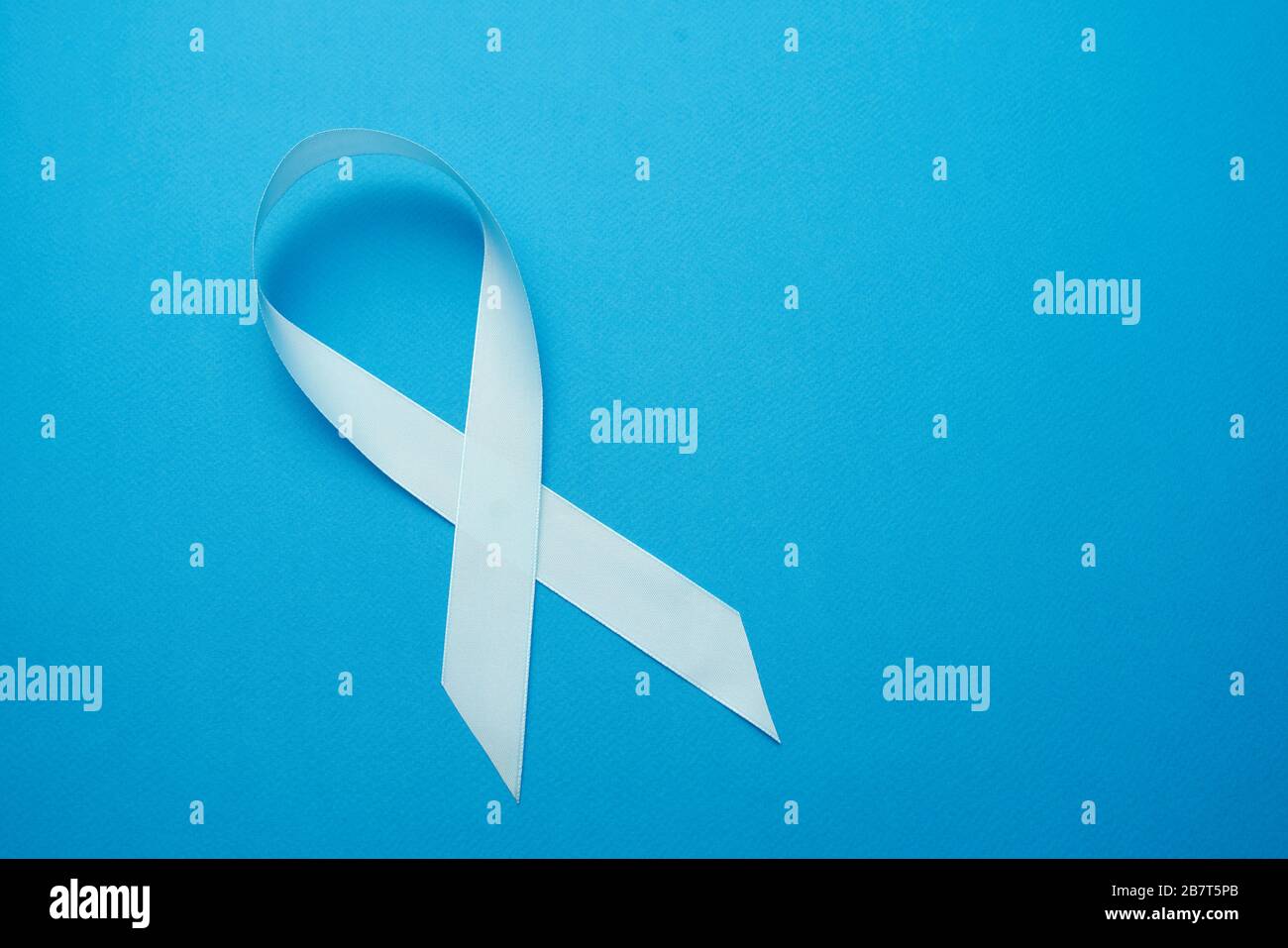 Crossed blue ribbon on blank background . Symbol of prostate cancer ...