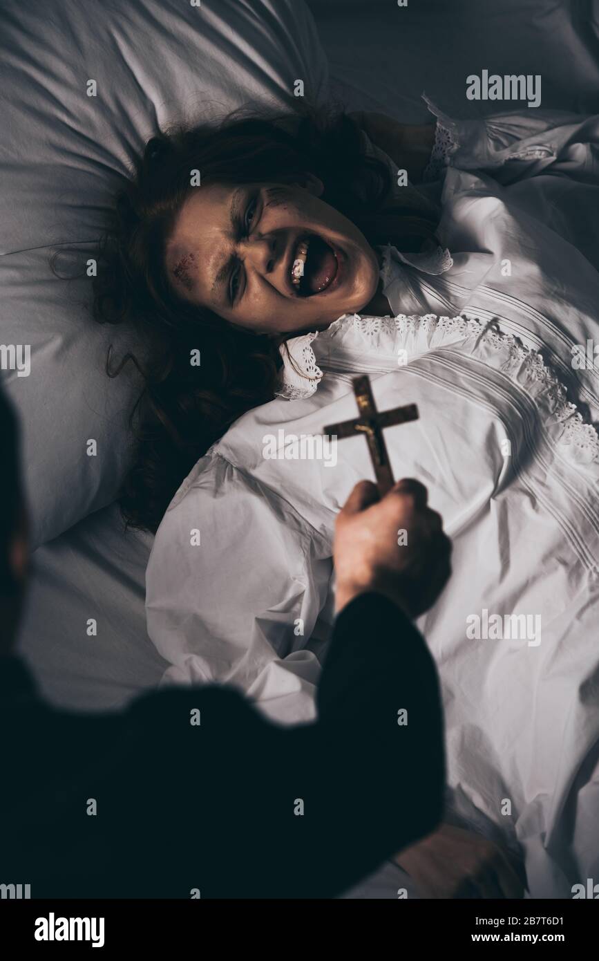 exorcist holding cross over creepy screaming demon in bed Stock Photo ...