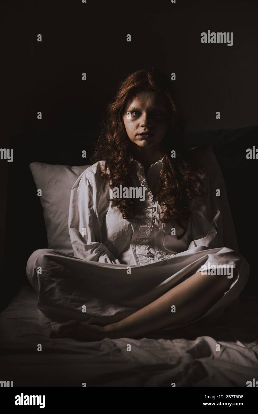 demonic young woman in nightgown sitting in bed Stock Photo - Alamy