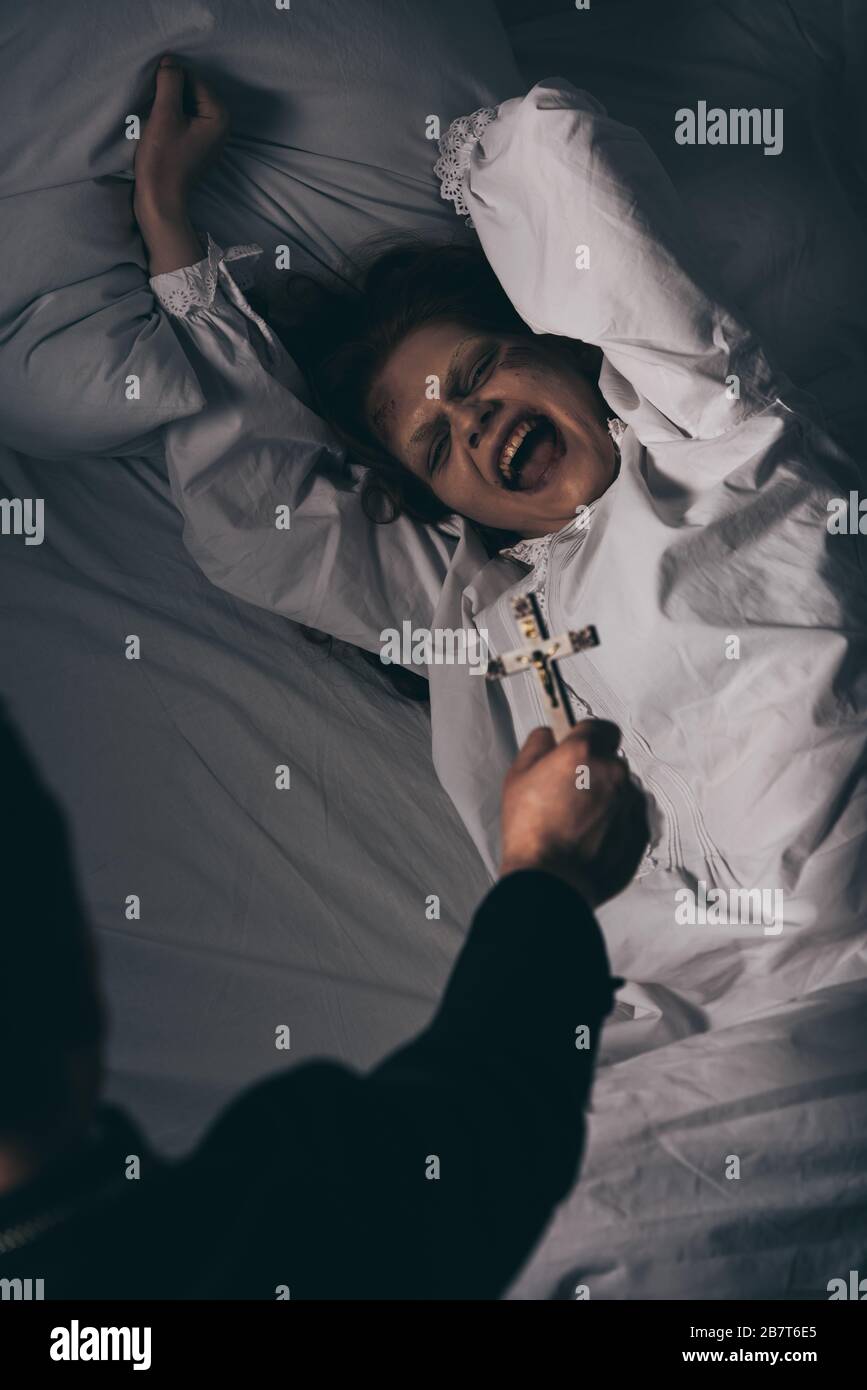 exorcist holding cross over creepy screaming demon in bed Stock Photo ...
