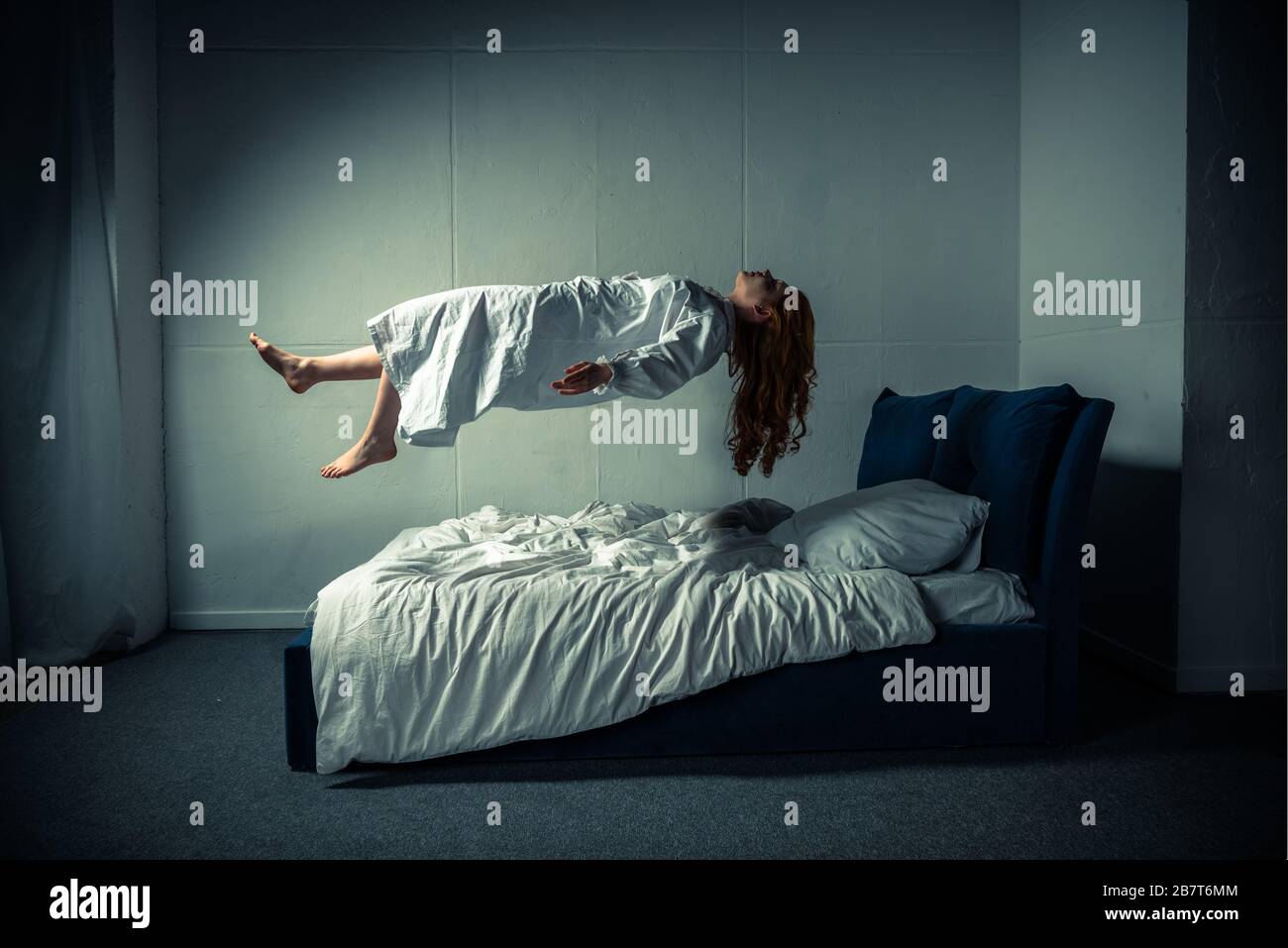 demonic girl in nightgown levitating over bed Stock Photo - Alamy