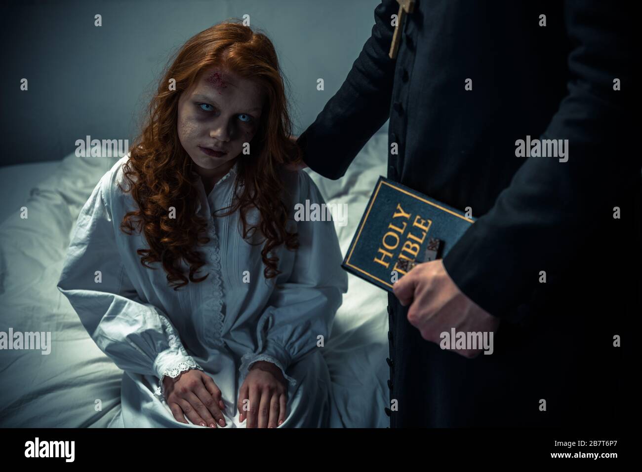 exorcist holding bible and hugging demoniacal girl in bedroom Stock ...