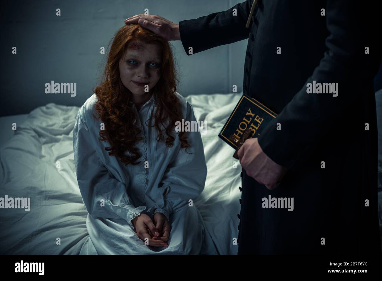 exorcist holding bible and hugging demonic creepy girl in bedroom Stock ...