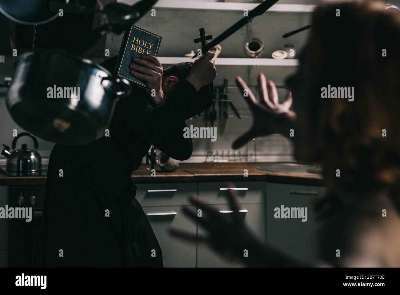 selective focus of evil demon with levitating cookware and exorcist ...