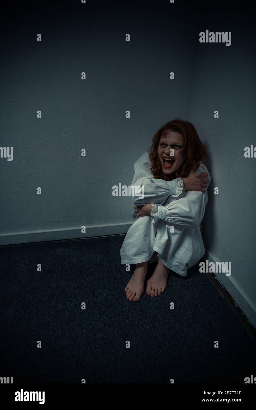 evil girl in nightgown shouting and sitting near wall Stock Photo - Alamy