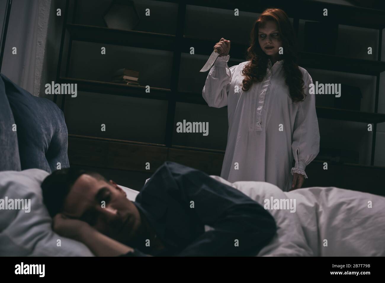 demoniacal creepy girl with knife standing over sleeping man in bedroom ...
