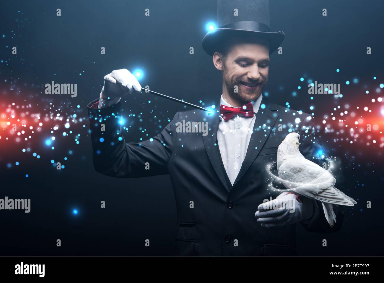 happy magician in hat making abracadabra with dove and wand in dark ...