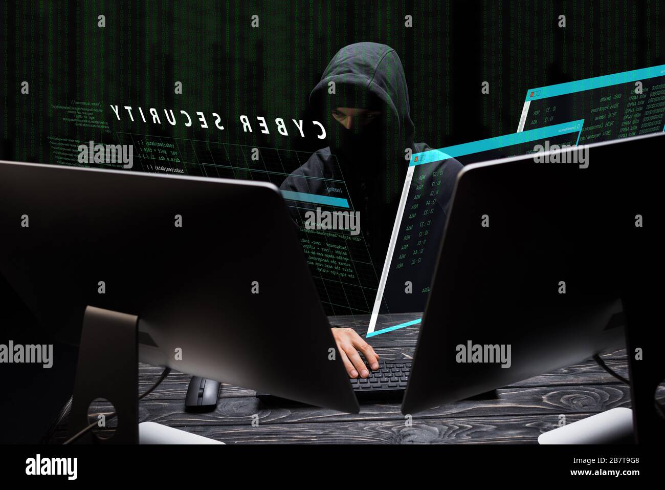 hacker in mask sitting near computer monitors and cyber security ...