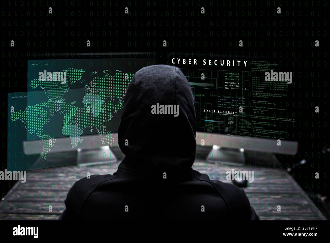 back view of hooded hacker sitting near computer monitors with cyber ...