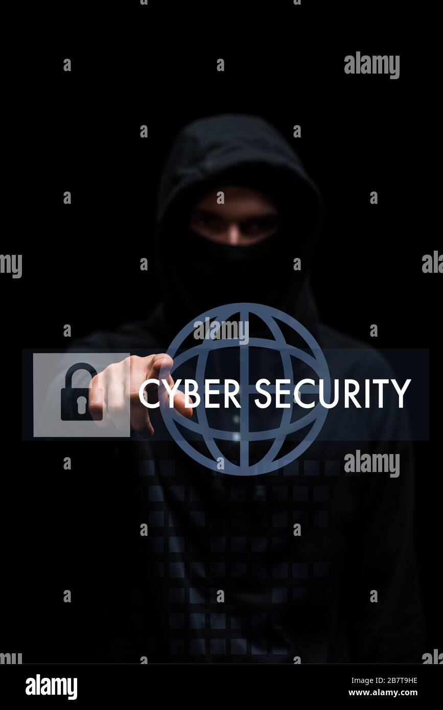 selective focus of hacker in hood pointing with finger at cyber ...