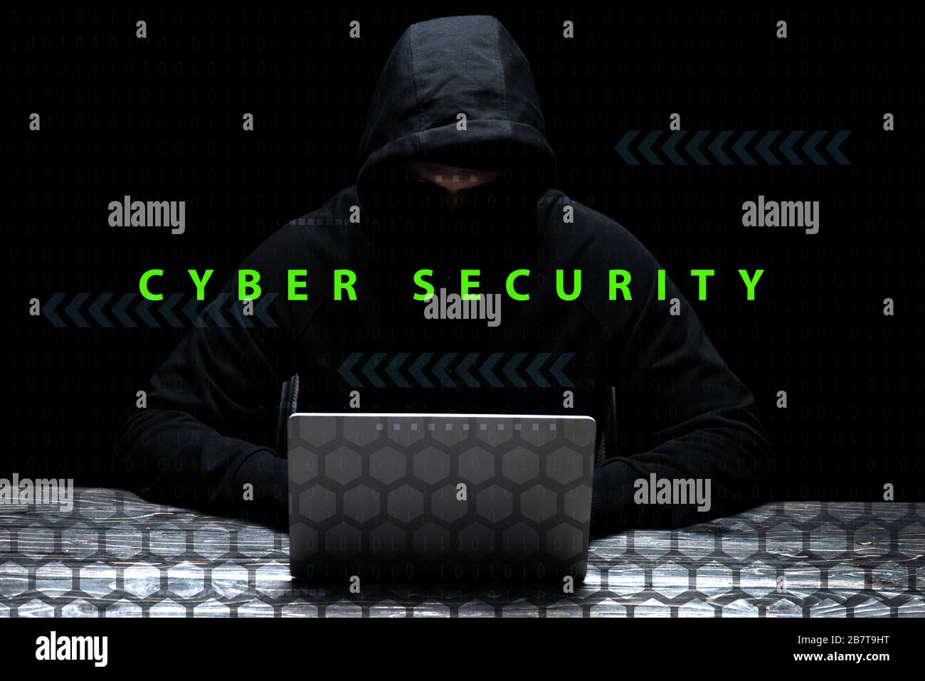 hacker in hood using laptop near cyber security lettering on black ...