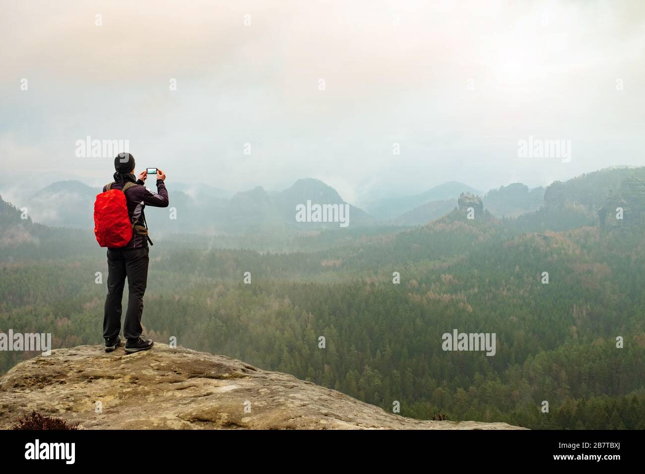 Red backpack hiker takes phone photos for social media. Modern ...
