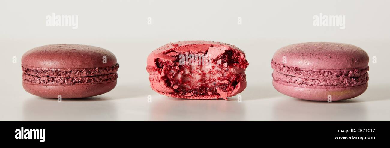 delicious whole and one bitten red french macaroons on white background ...