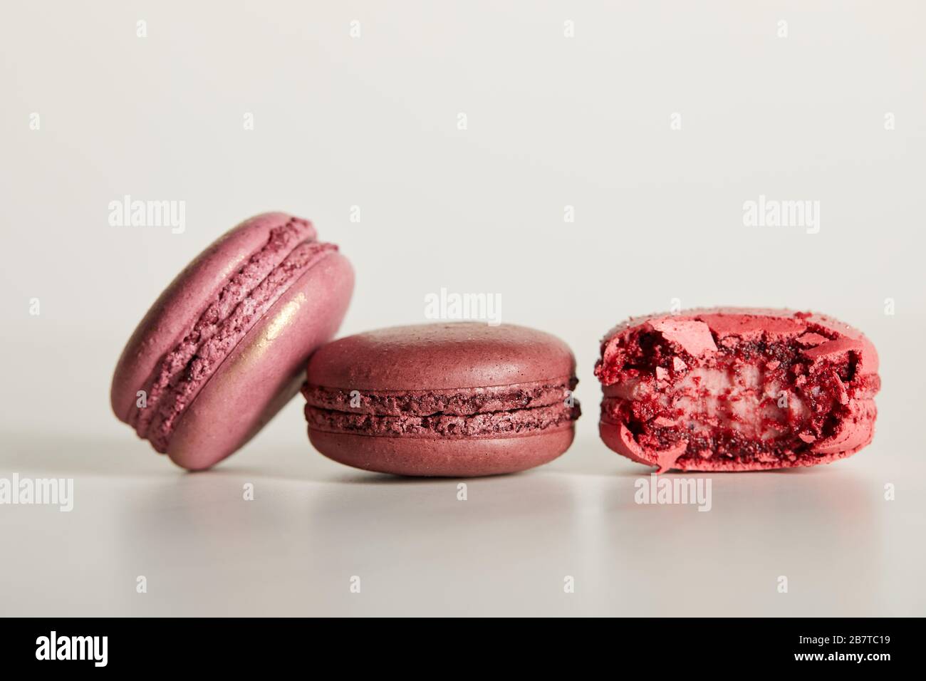 delicious whole and one bitten red french macaroons on white background ...