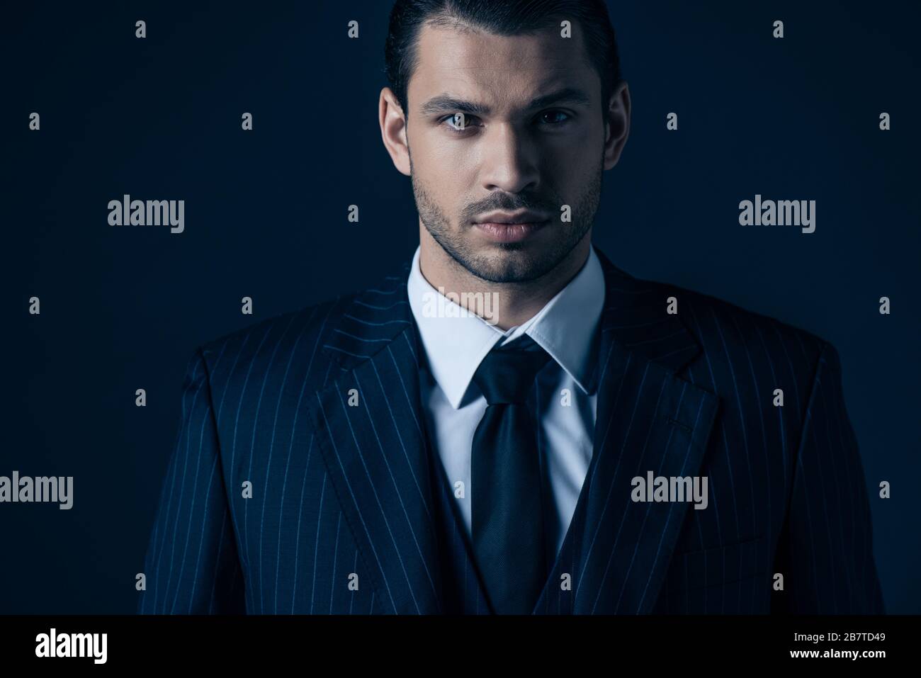 Front view of mafioso looking at camera on dark blue Stock Photo - Alamy