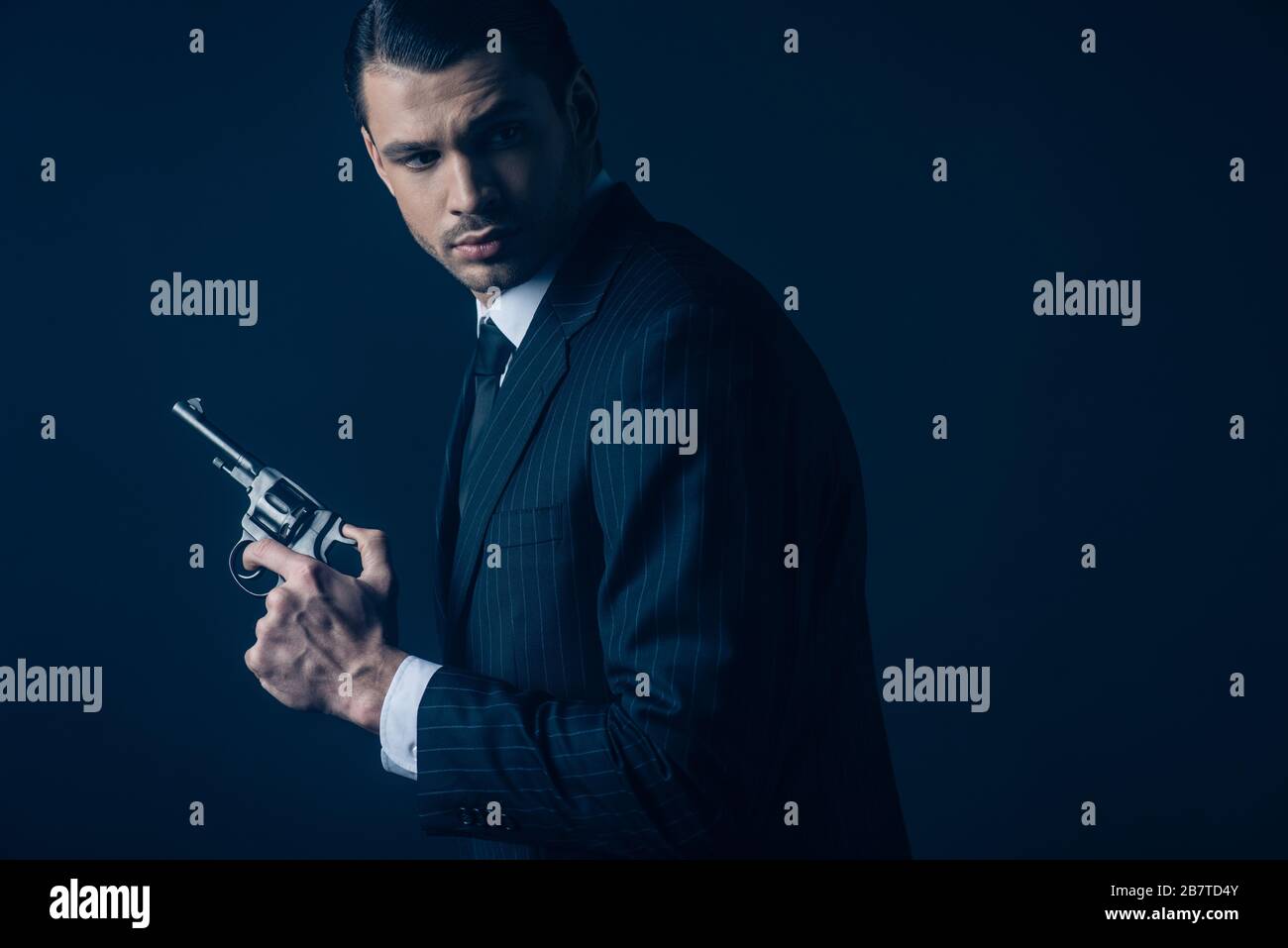 Side view of gangster with revolver on dark background Stock Photo - Alamy