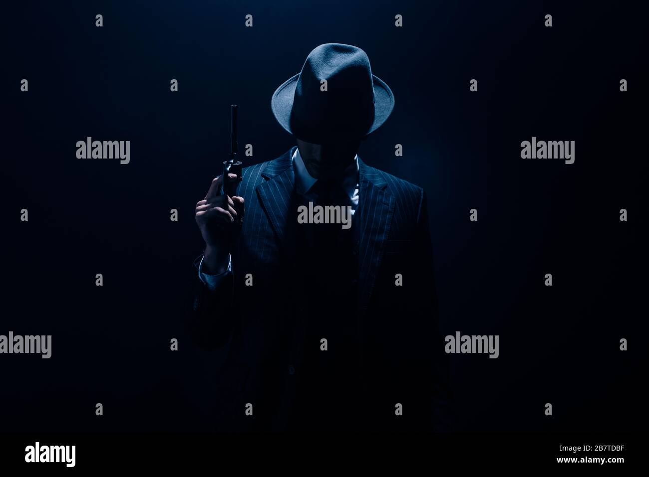 Silhouette of gangster raising gun on dark blue background Stock Photo ...