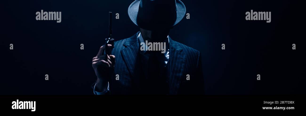 Silhouette of gangster raising gun on dark blue background, panoramic ...