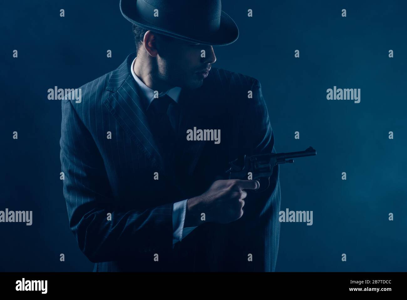 Gangster pointing revolver aside on dark blue background Stock Photo ...