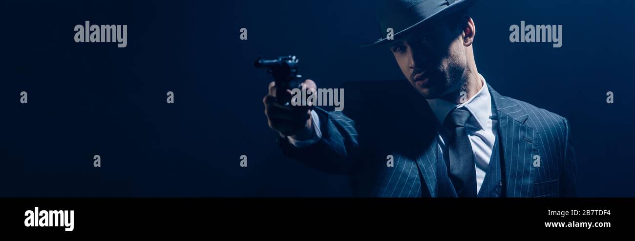 Gangster aiming weapon with outstretched hand on dark background ...