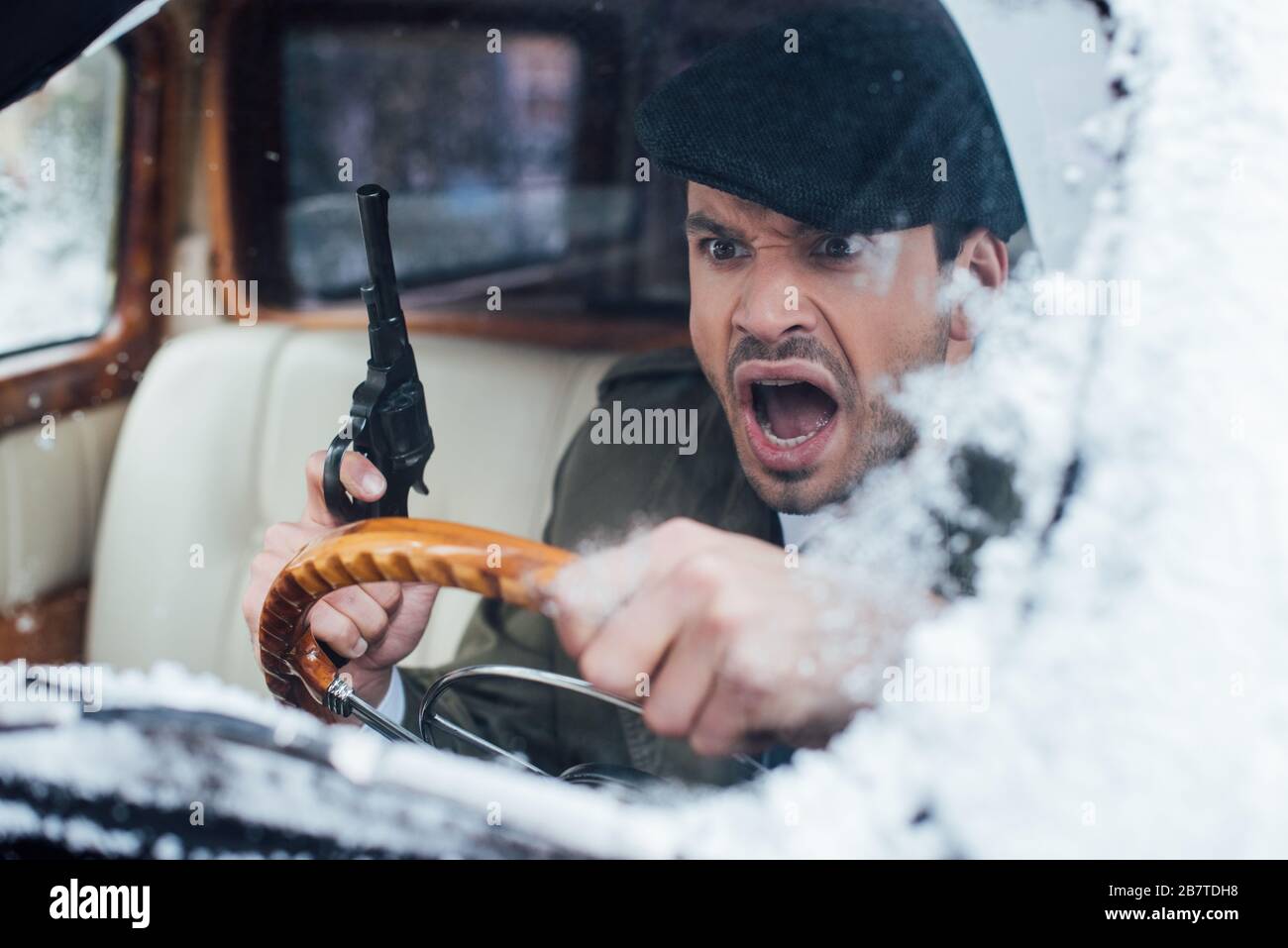 Selective focus of angry gangster with gun driving car Stock Photo - Alamy