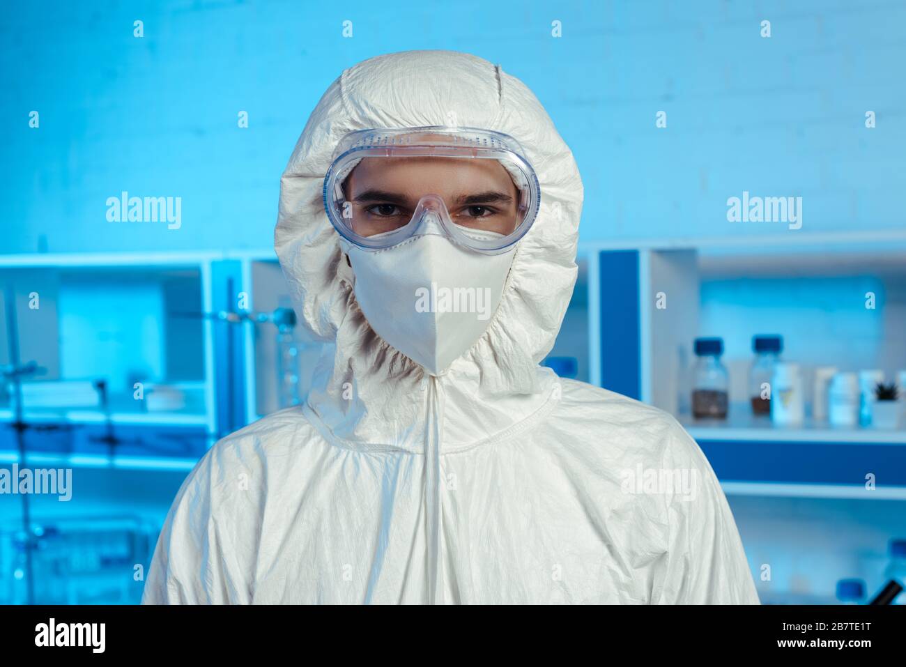 scientist in hazmat suit, medical mask and goggles looking at camera ...