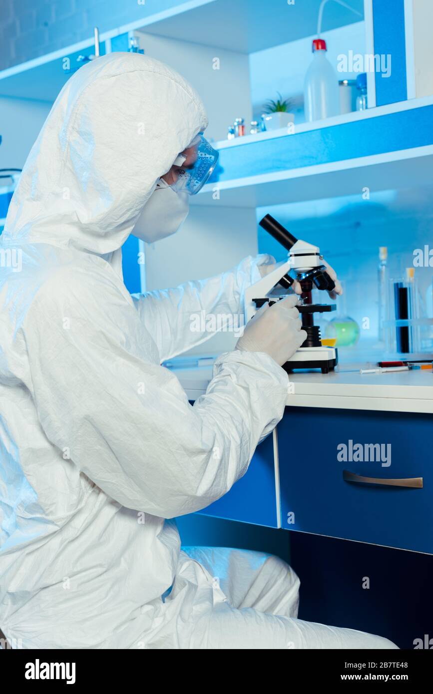 scientist in hazmat suit and goggles near microscope in laboratory ...