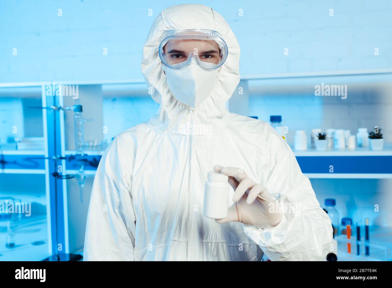 scientist in hazmat suit and goggles holding bottle in laboratory Stock ...