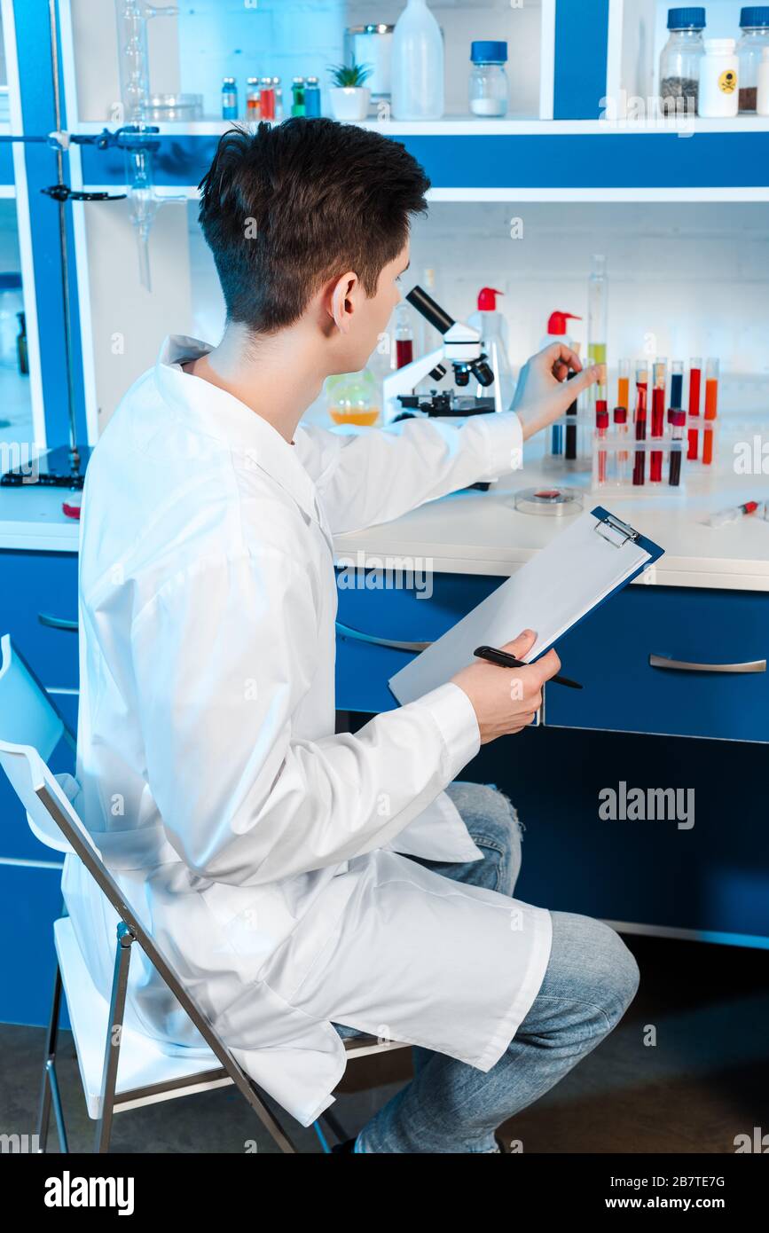 scientist in white coat holding clipboard and touching test tube Stock ...