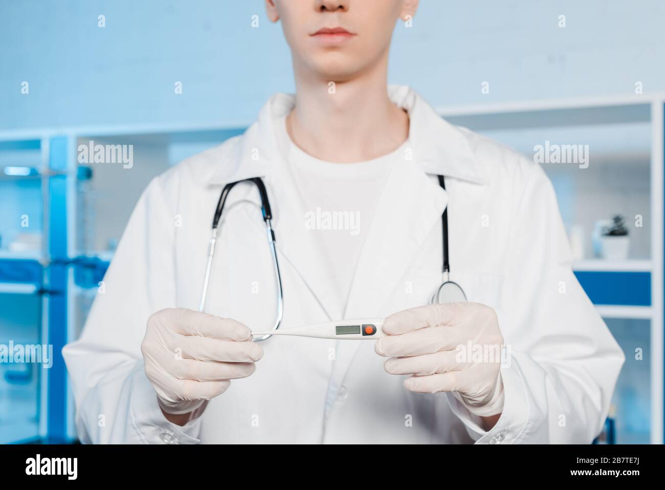 cropped view of scientist in latex gloves holding digital thermometer ...