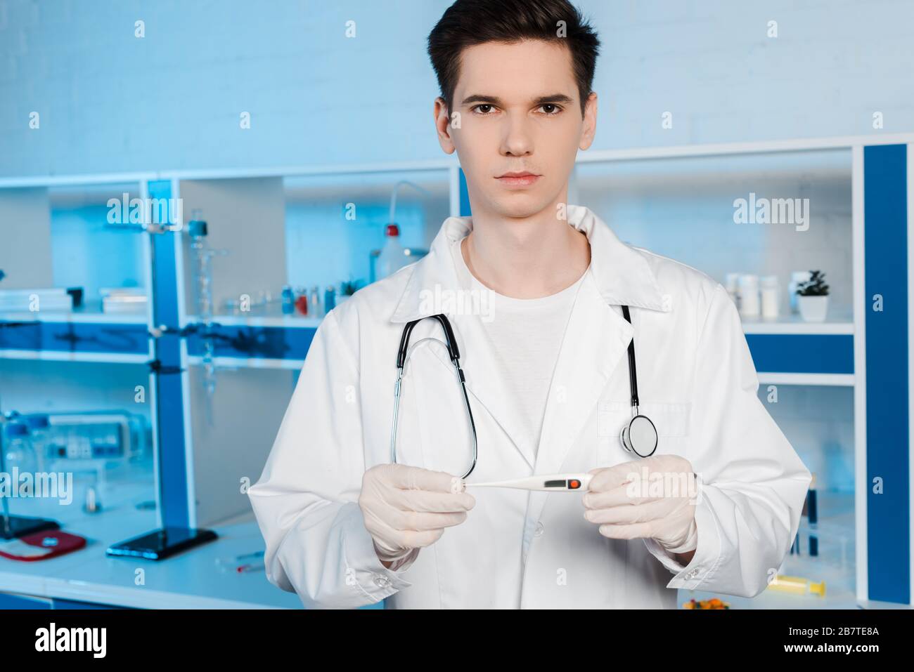 handsome scientist in latex gloves holding digital thermometer Stock ...