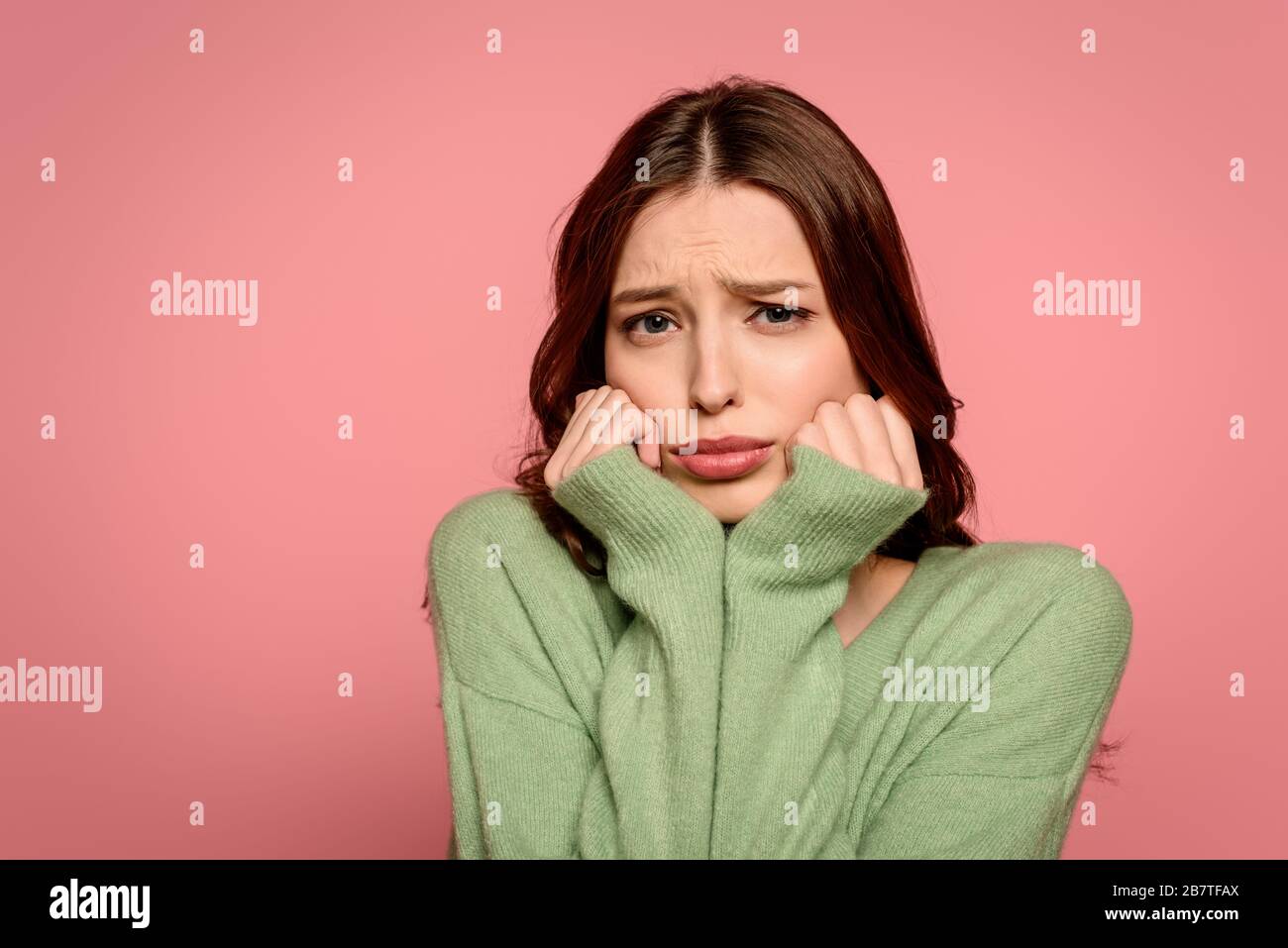 offended girl looking at camera while holding hands near face isolated ...