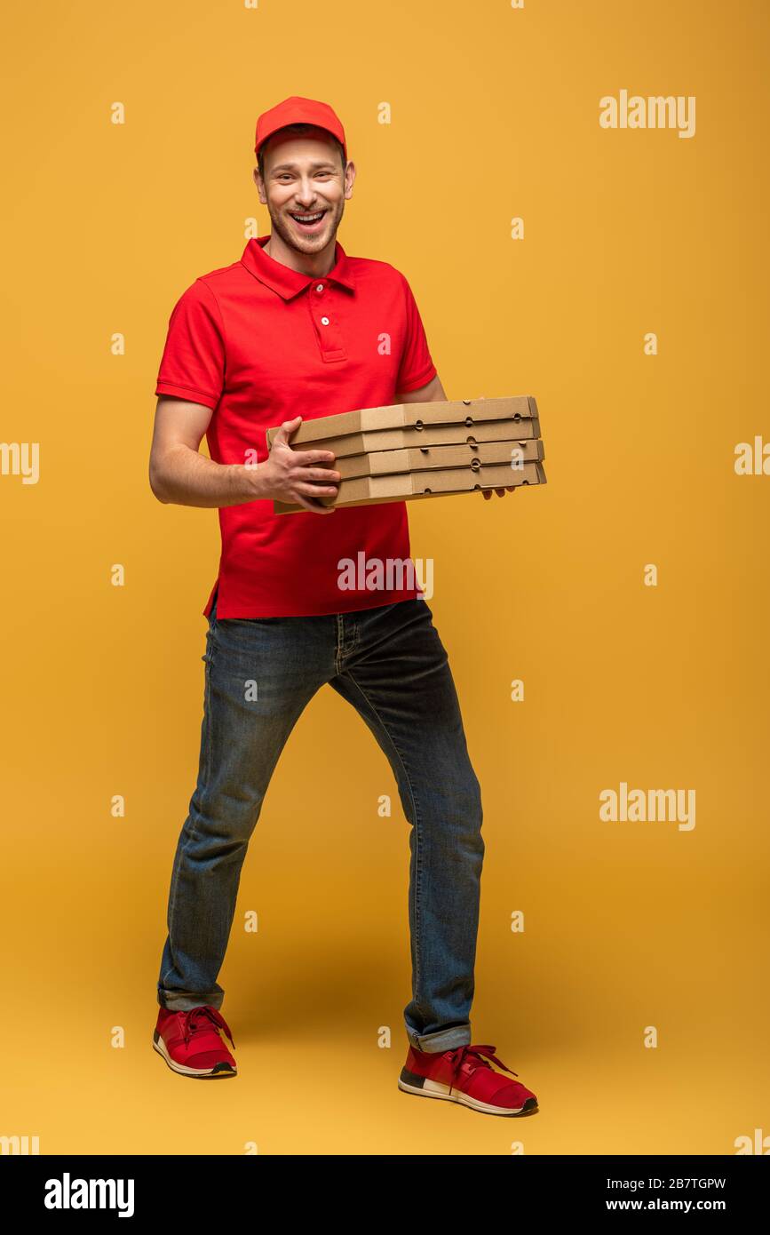 full length view of happy delivery man in red uniform walking with ...