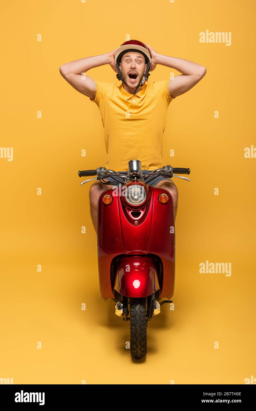 shocked delivery man in yellow uniform riding scooter on yellow ...