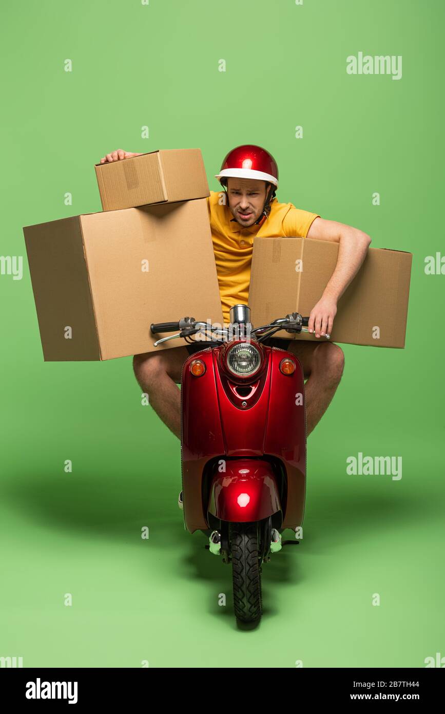 tired delivery man in yellow uniform on scooter with boxes on green ...